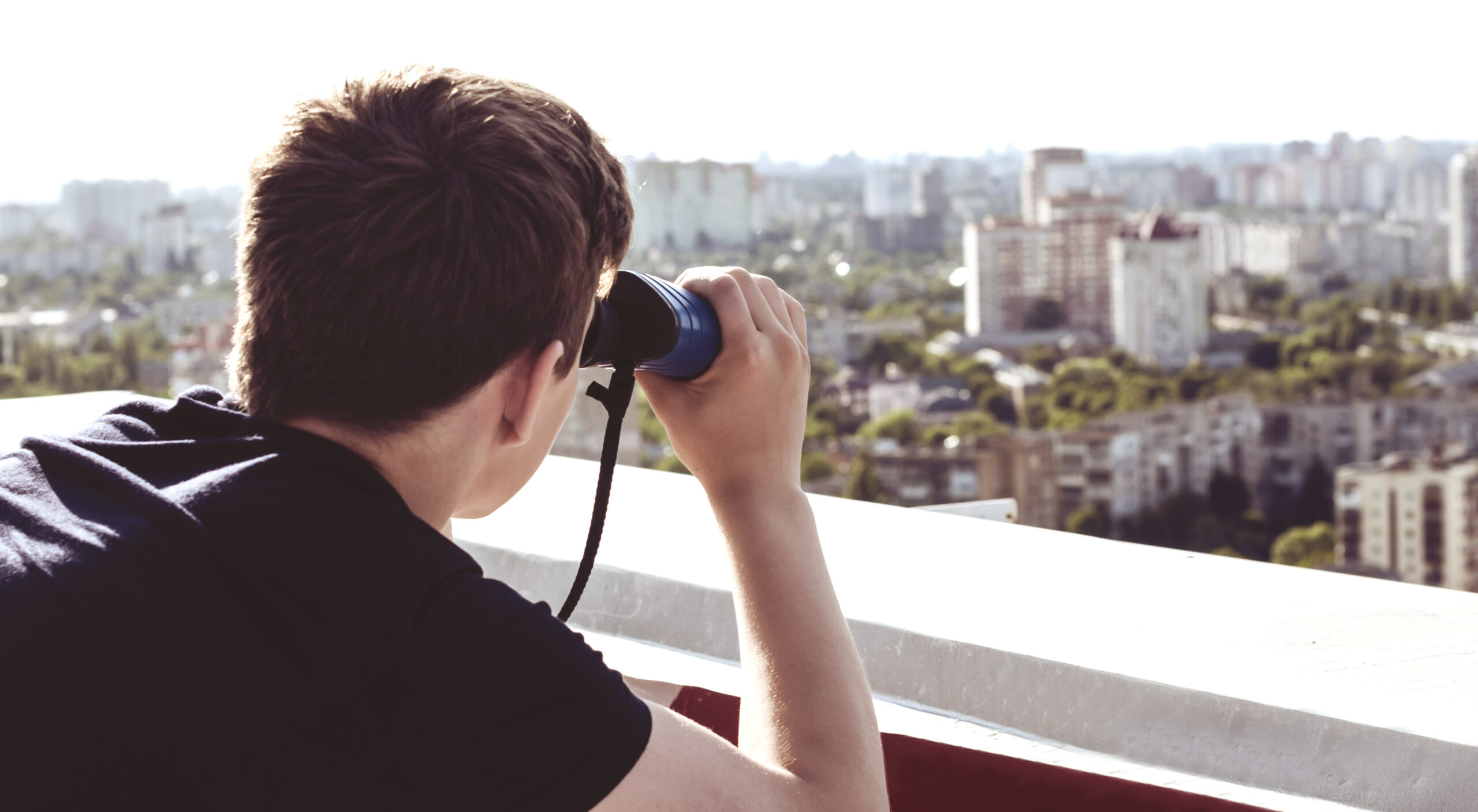 A young man with binoculars watching from the roof of the house - Jo Garner